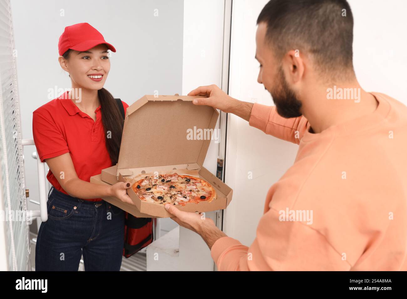 Female courier giving ordered pizza to client Stock Photo - Alamy