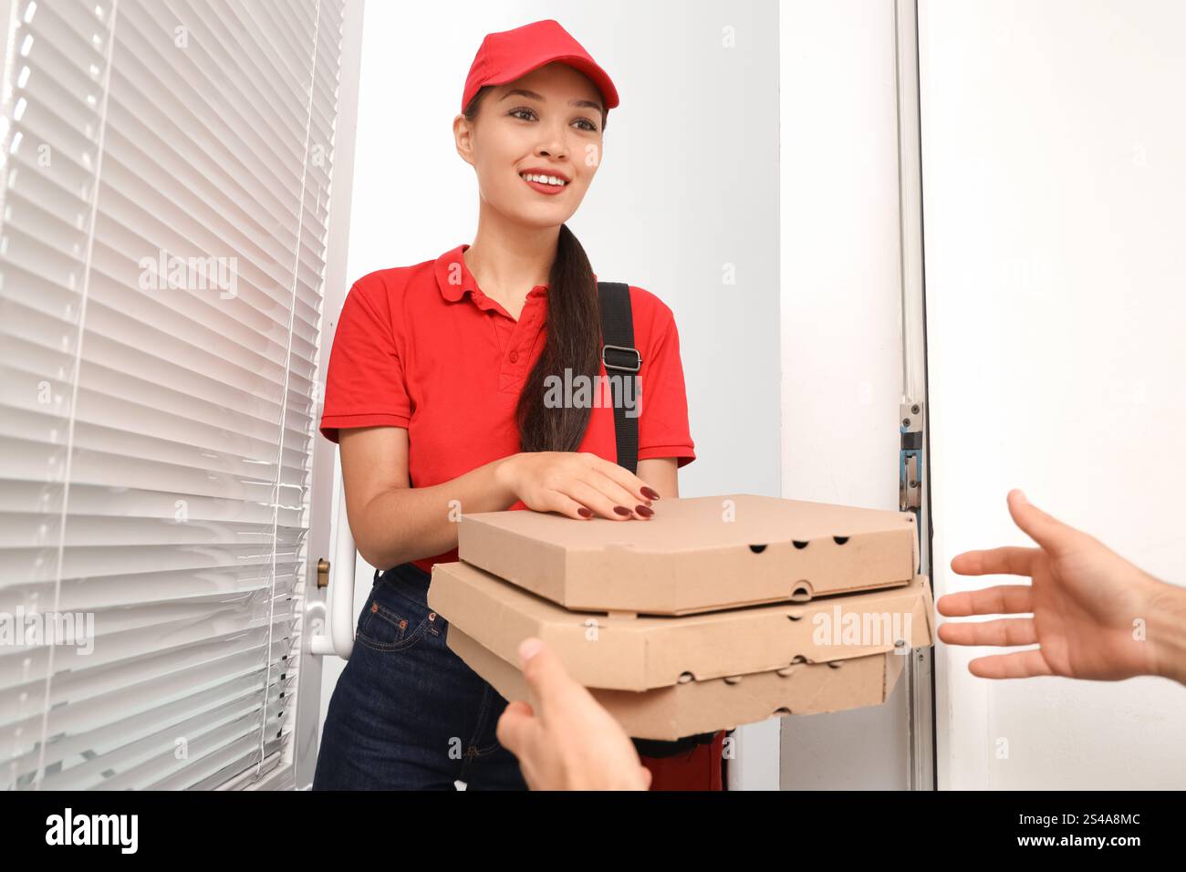 Female courier giving ordered pizza to client Stock Photo - Alamy