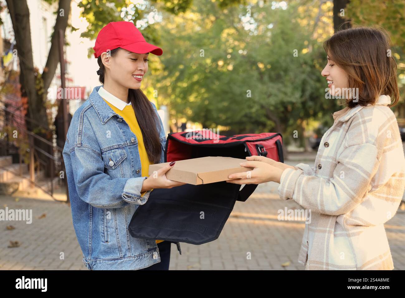 Female Asian courier giving ordered pizza to client outdoors Stock Photo - Alamy