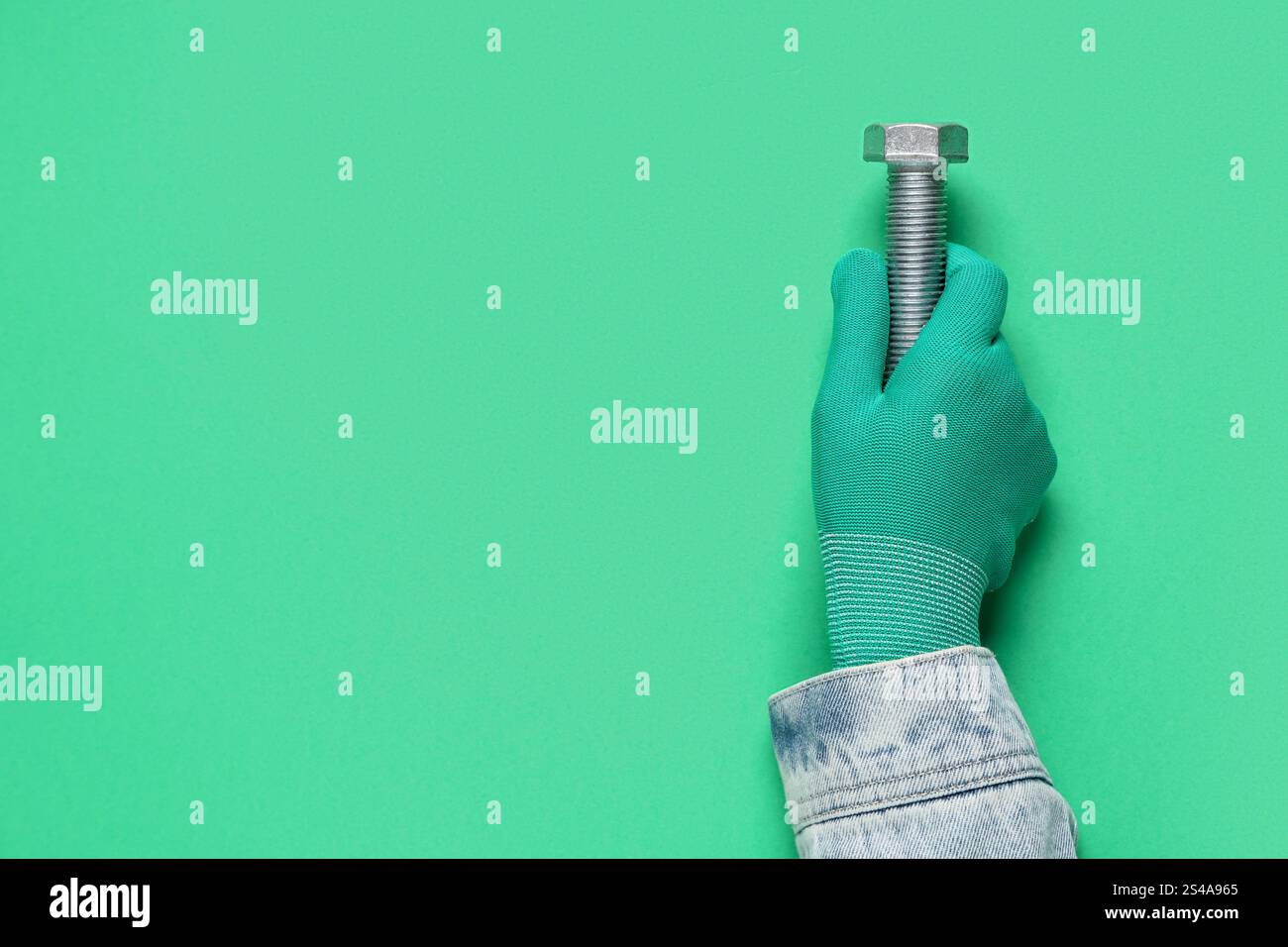 Mechanic's hand holding bolt on green background Stock Photo - Alamy