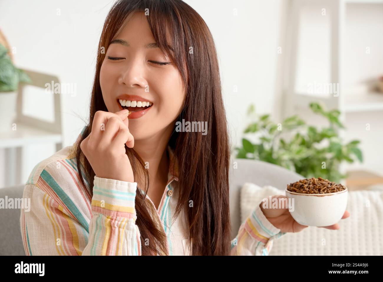 Beautiful Asian woman eating fried insects at home, closeup Stock Photo ...