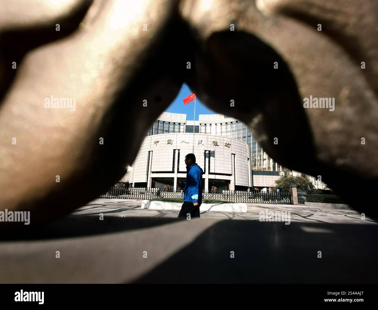 A citizen passes the headquarters building of the People's Bank of ...