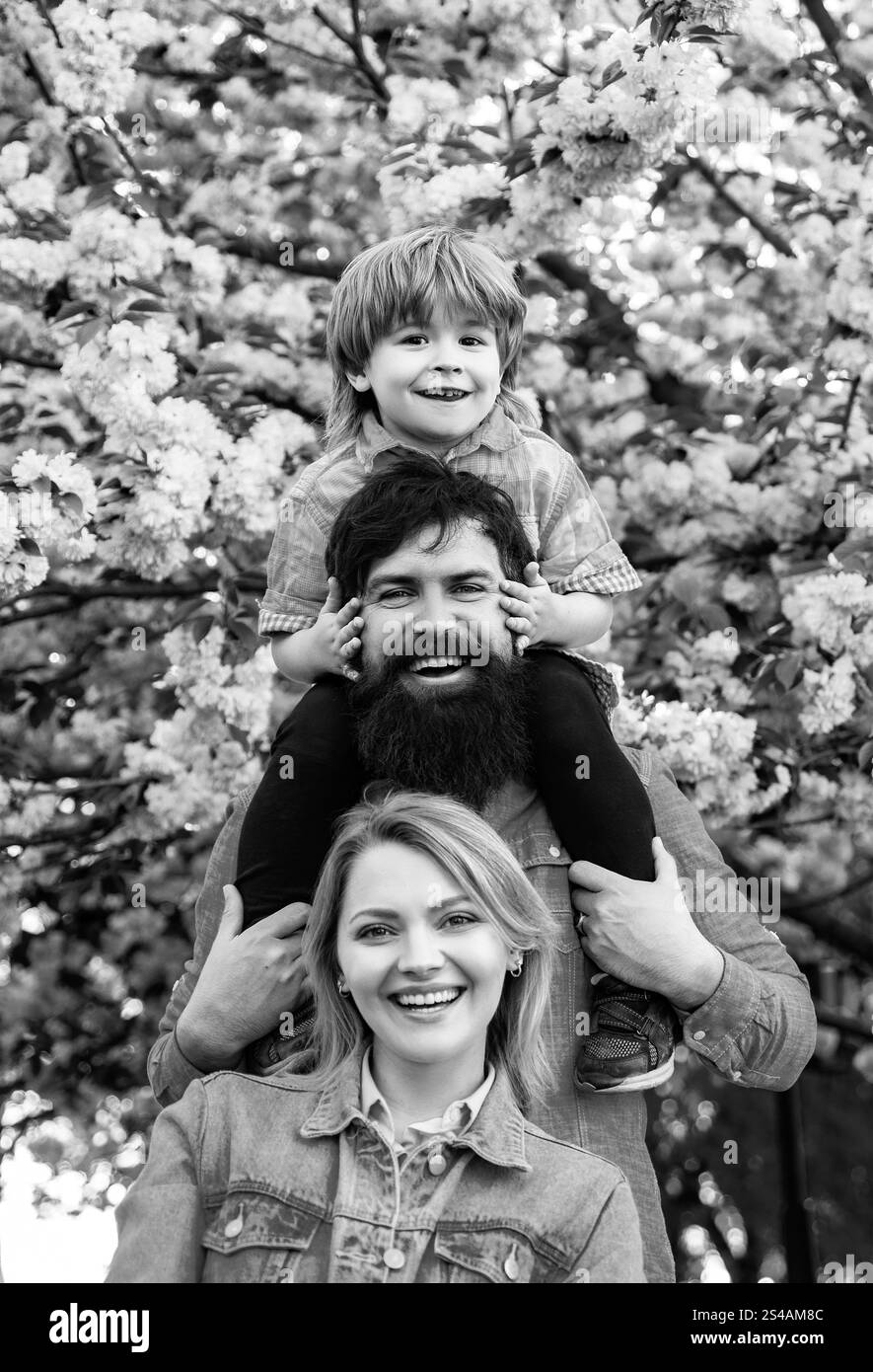 Parents giving piggyback ride to child. Happy family outdoors. Mother ...