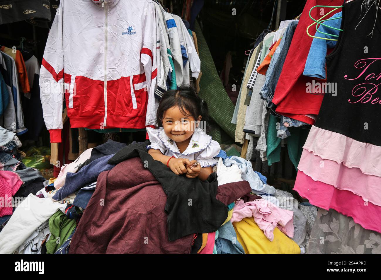 A young baby girl emerges from a pile of clothes playing peekaboo with passersby in a second ...
