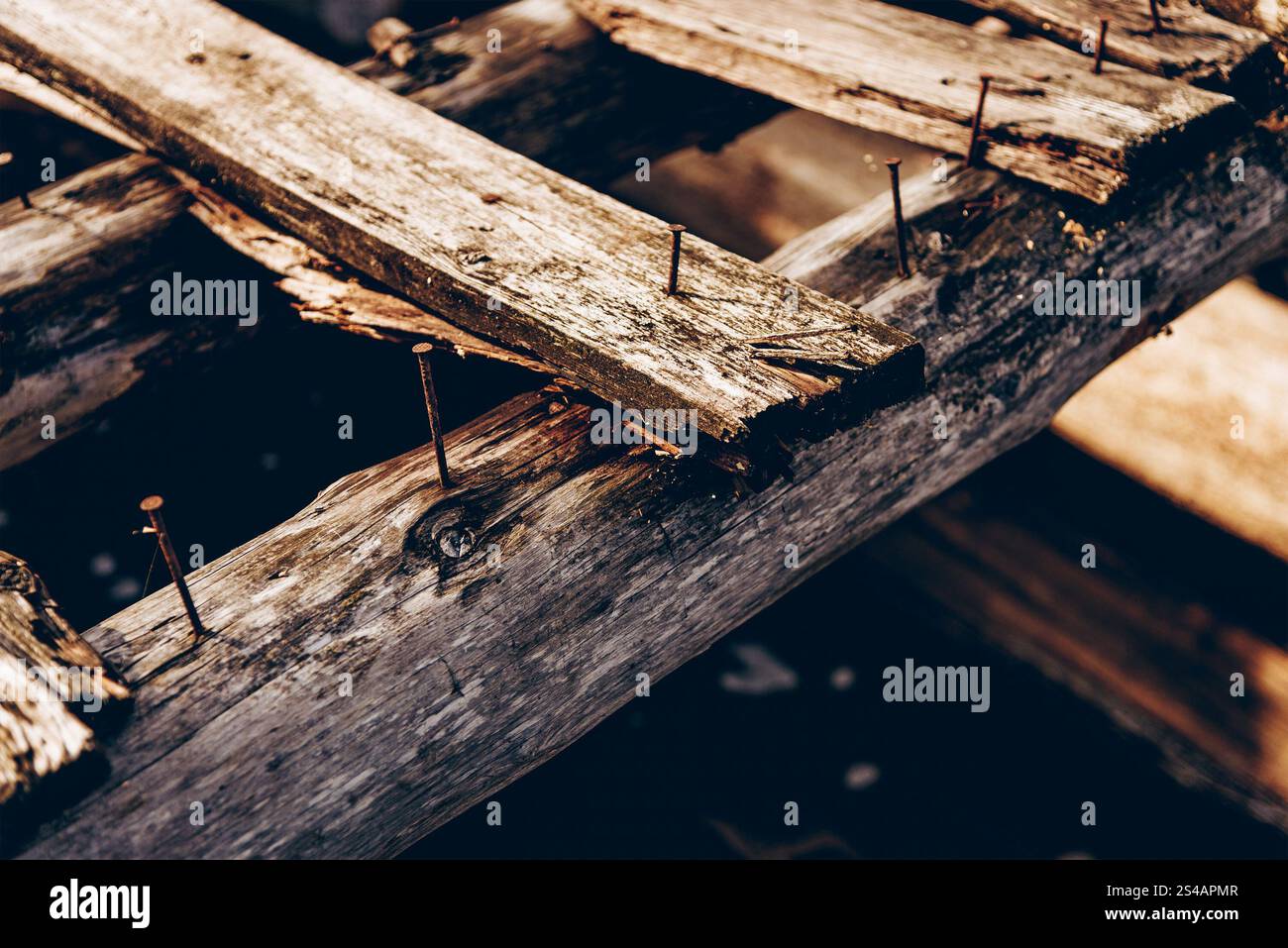 Old rusty nails sticking out of a wooden collapsed bridge, structural ...