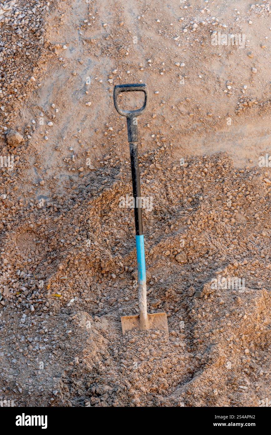 Old dirty shovel stuck in a pile of sand soil, building construction ...