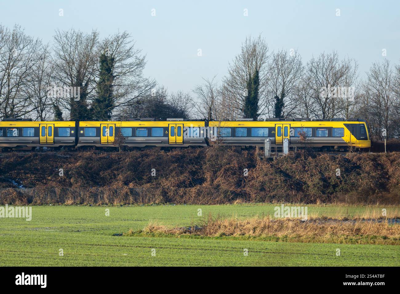 Merseyrail train arriving at Maghull rail station. Crossing an old iron ...