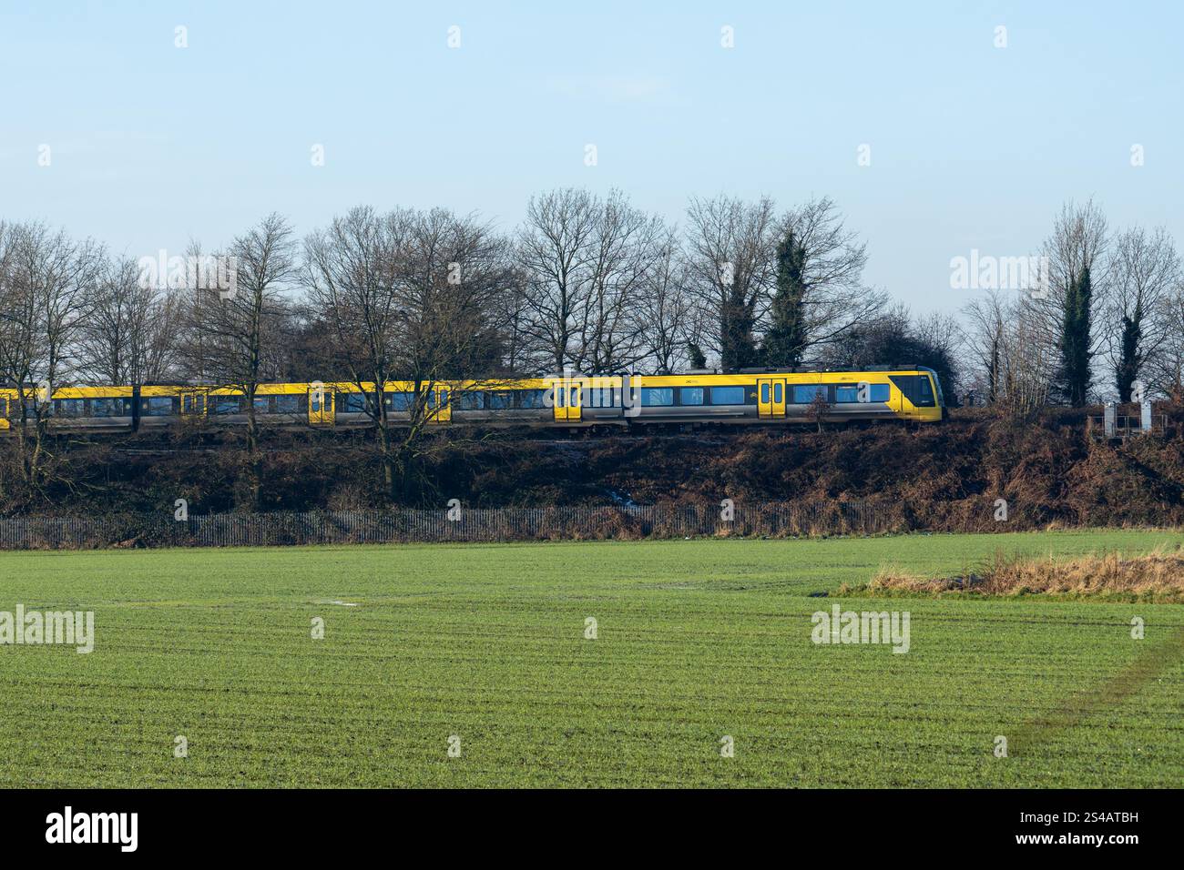 Merseyrail train arriving at Maghull rail station. Crossing an old iron ...