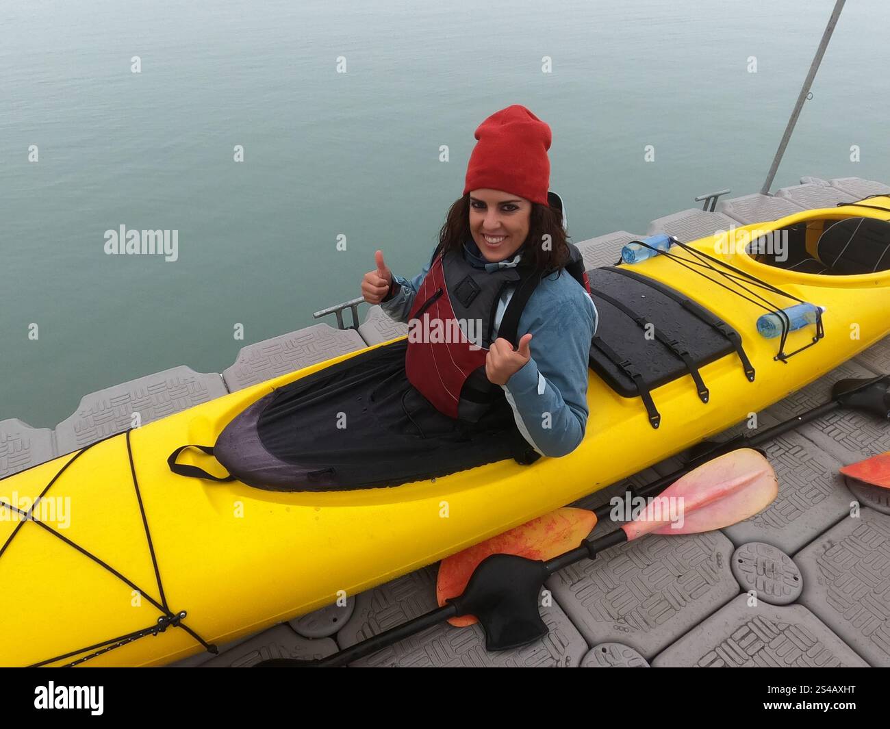 Young brunette woman in a yellow kayak giving a thumbs-up gesture ...