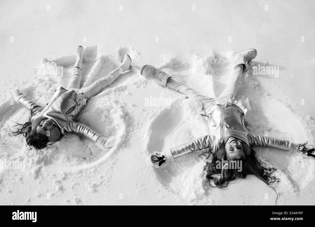 Smiling children lying on snow with copy space. Funny kids making snow ...