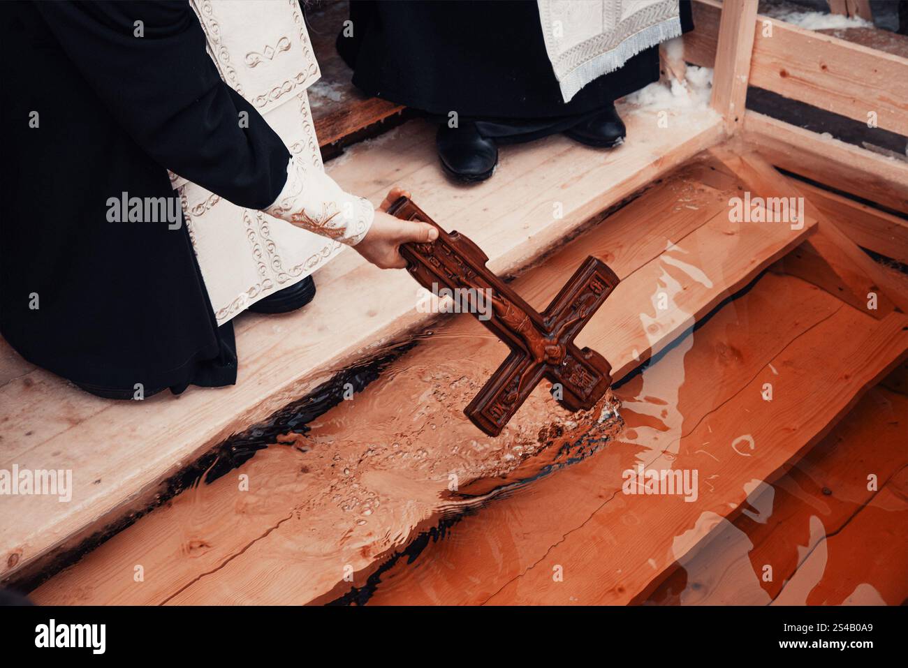Priest consecrating river water for baptism, holy father holding cross crucifix in hand close up ...