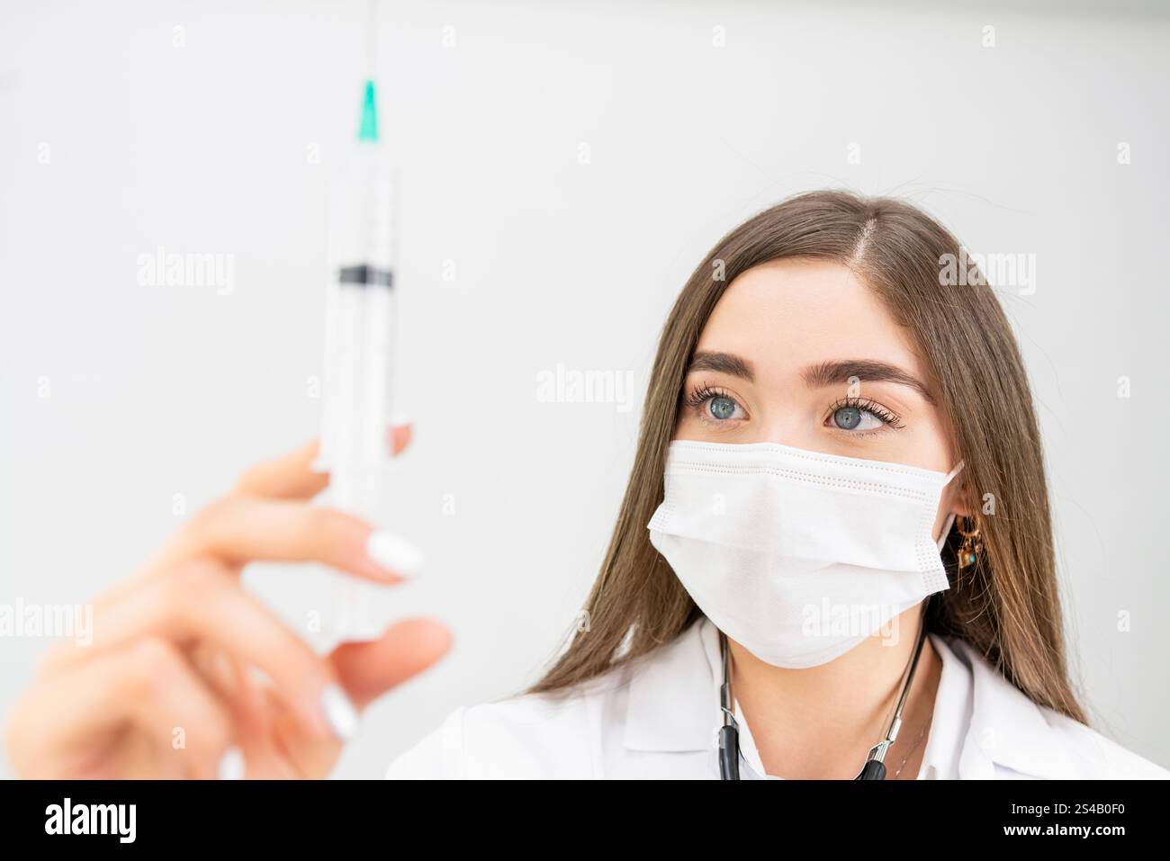 Female doctor in a white coat prepares a syringe for injection Stock ...