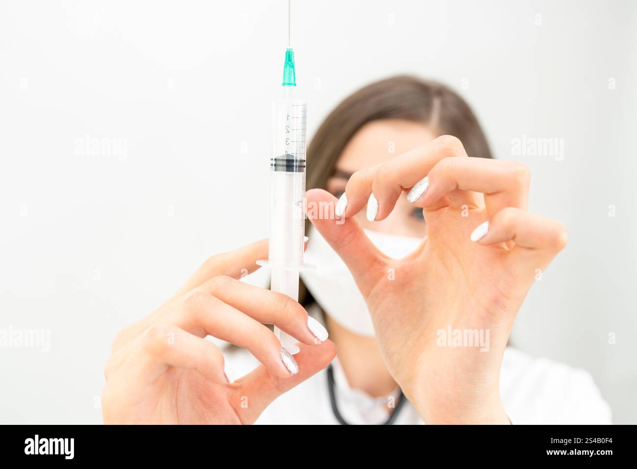 Female doctor in a white coat prepares a syringe for injection Stock ...