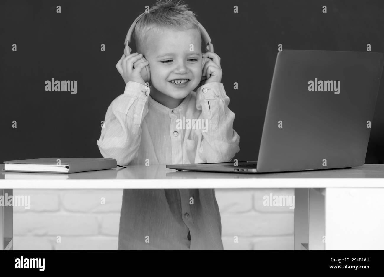 Child boy in headphones using a laptop and study online with video call ...