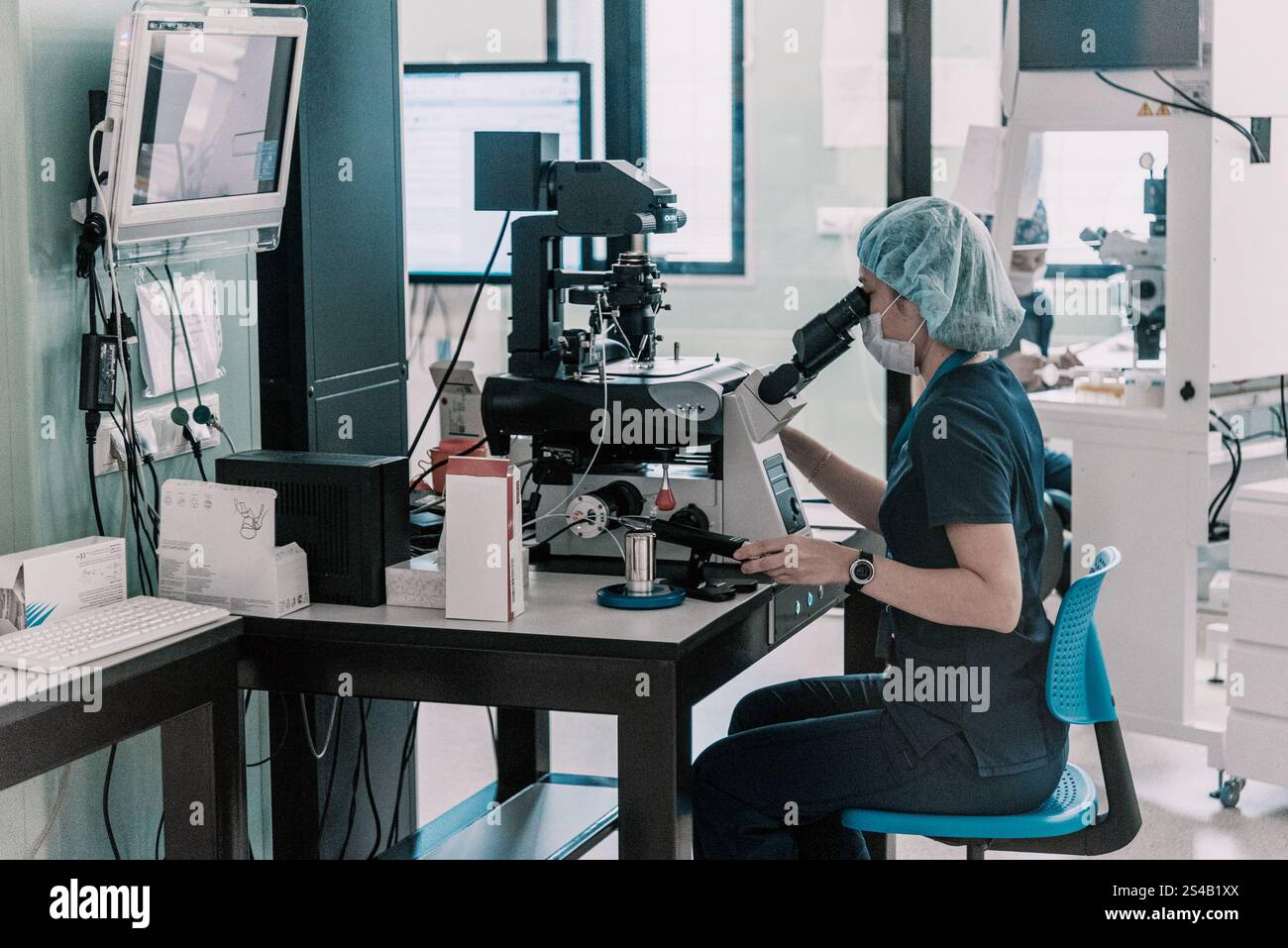 Woman laboratory assistant looking at analysis sample under microscope ...