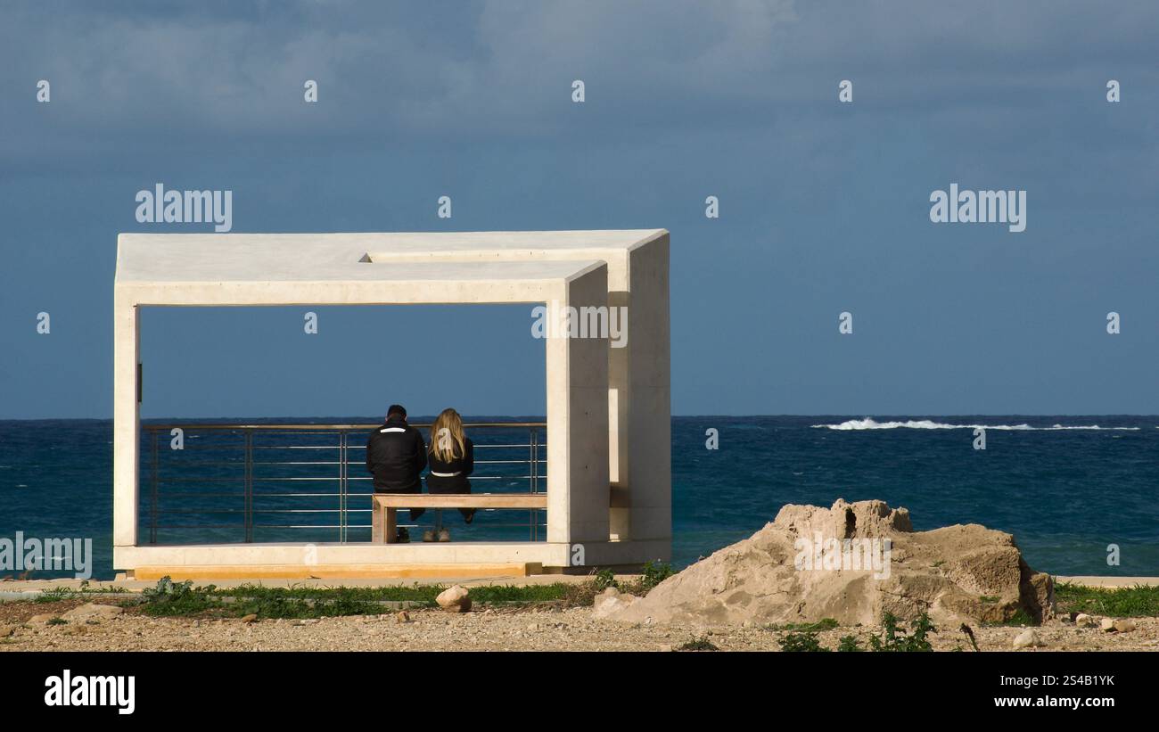 Two People Sitting by a Modern Shelter Overlooking a Vast Blue Ocean ...
