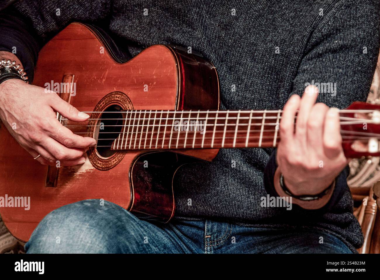 Man plays the strings of a guitar, a musician guitarist performs at a ...