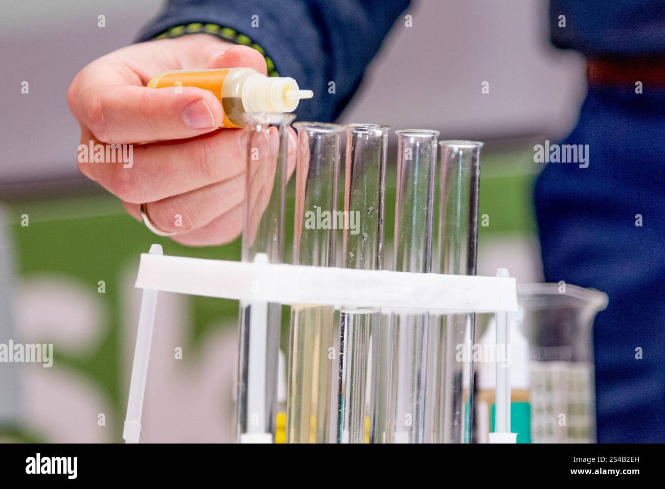 Scientist in laboratory pours liquid into glass flask, assistant ...