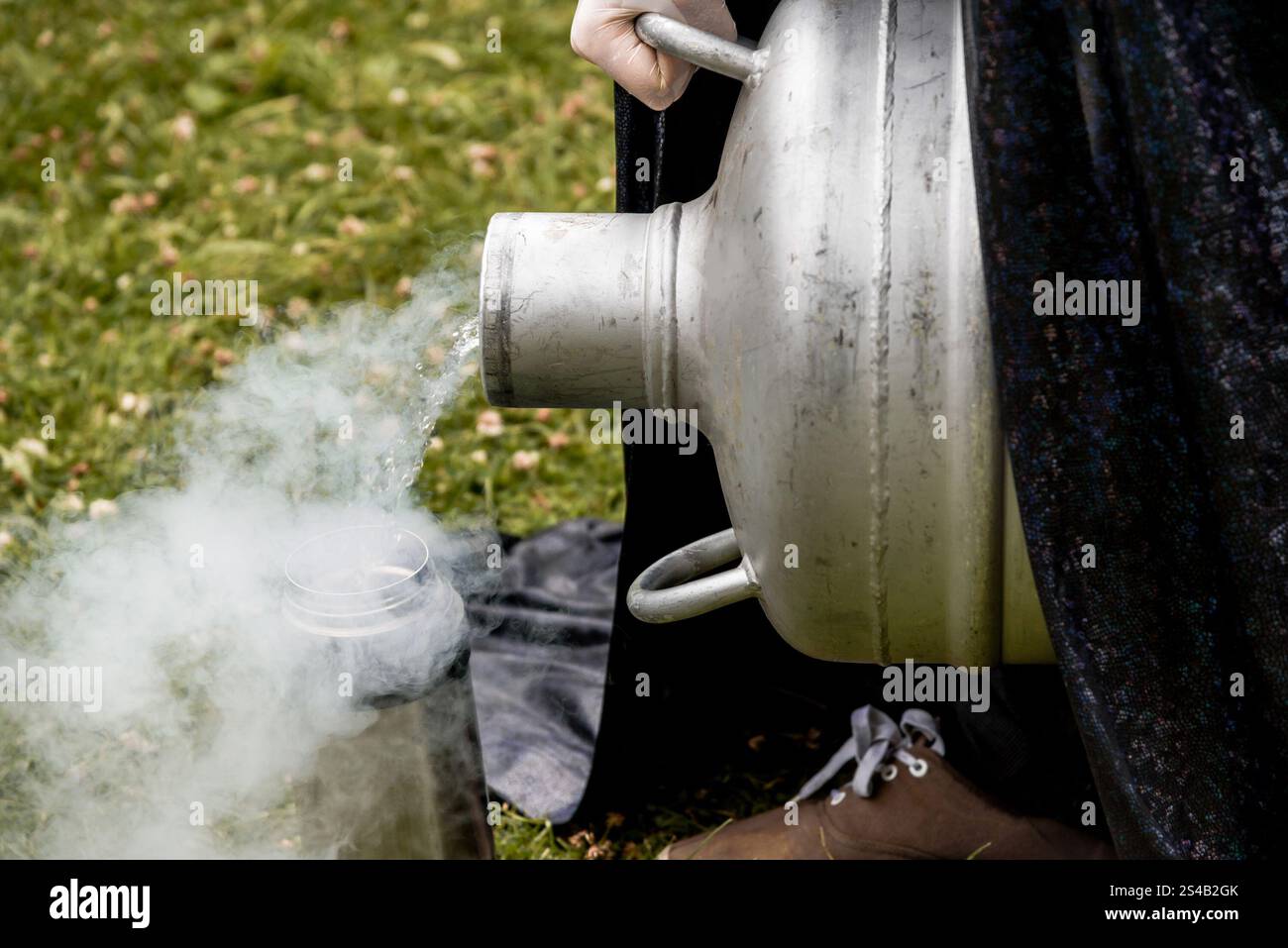 Scientist pours liquid nitrogen from large metal barrel into flask ...