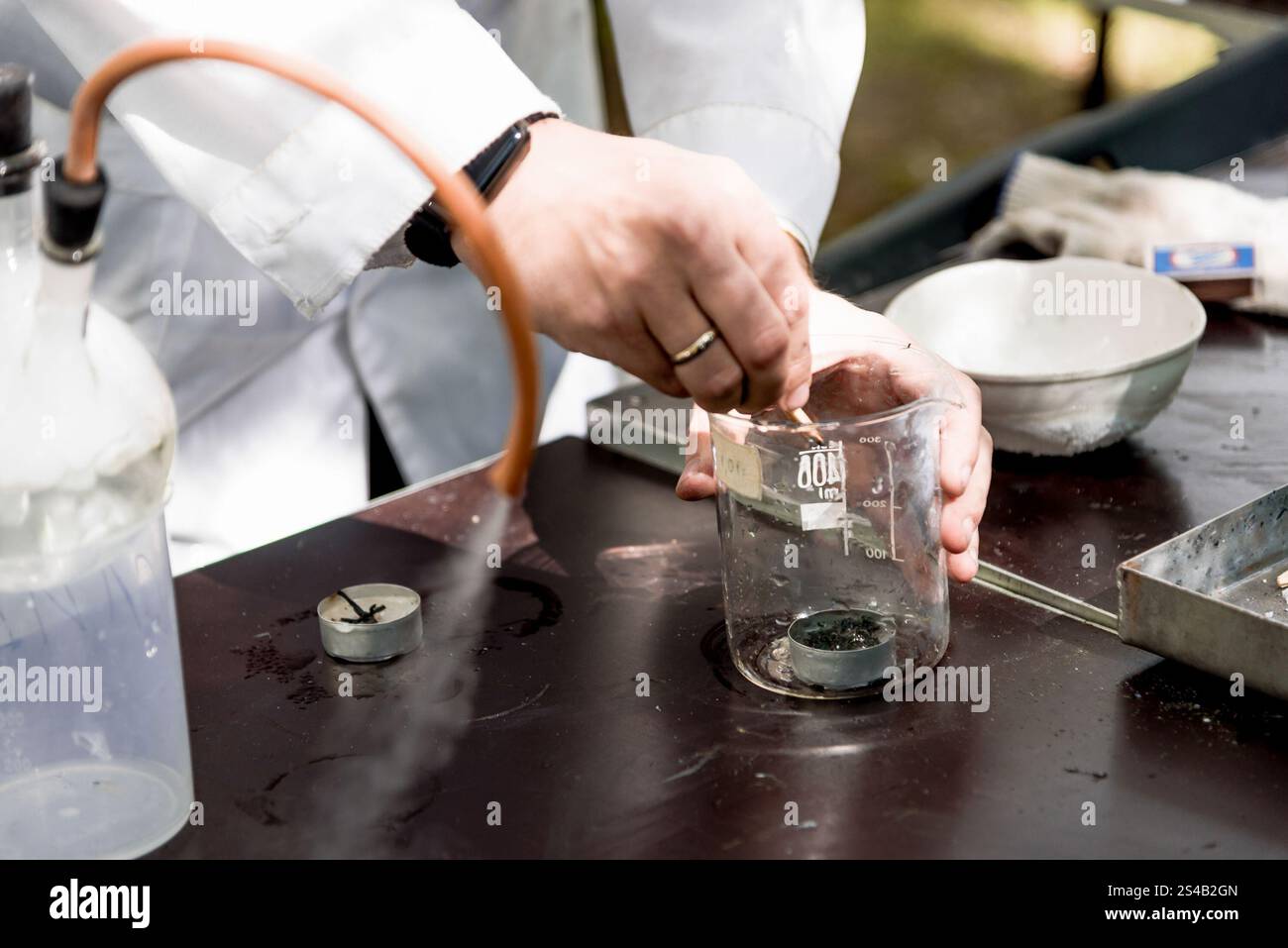 Scientist in laboratory pours liquid into glass flask, assistant ...