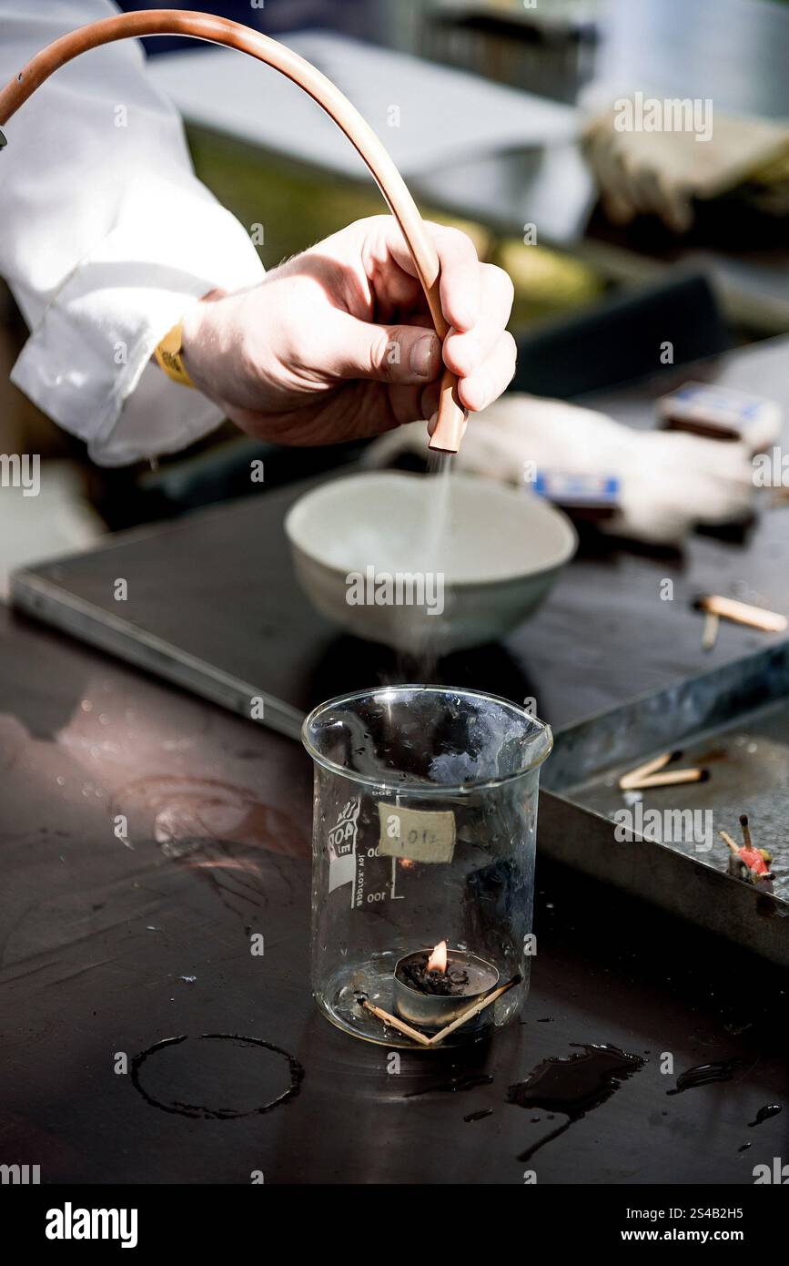 Scientist in laboratory pours liquid into glass flask, assistant ...