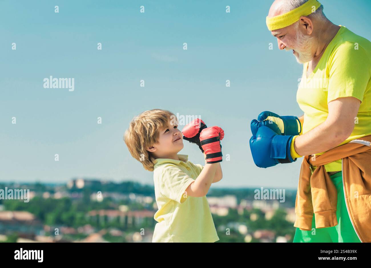 Grandpa and little child boy in boxing stance doing exercises with ...
