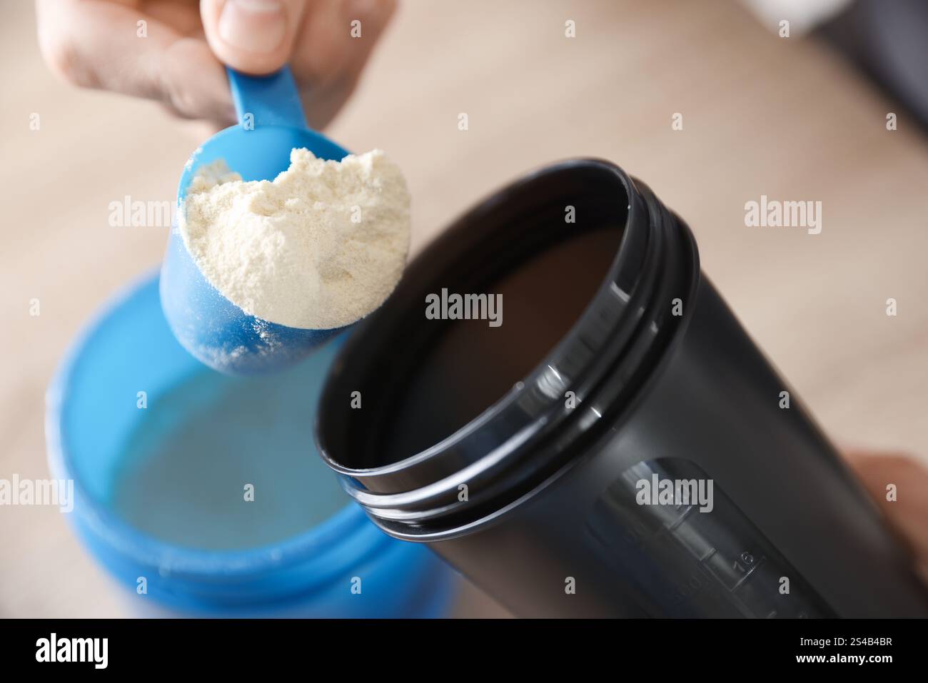 Making protein cocktail. Man adding powder into shaker at table ...