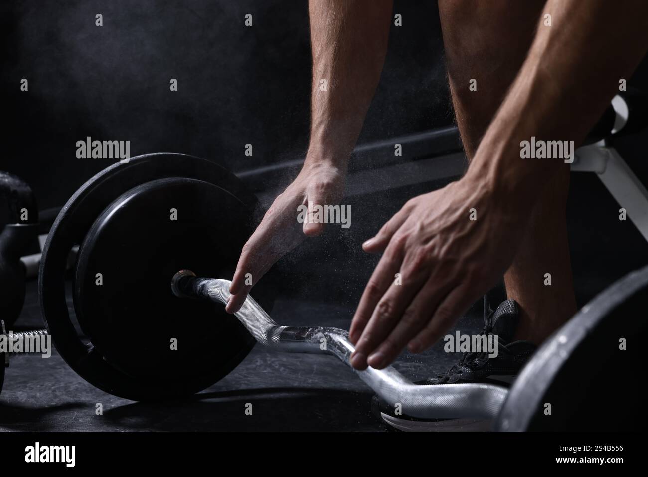 Man clapping hands with talcum powder before training with barbell in ...