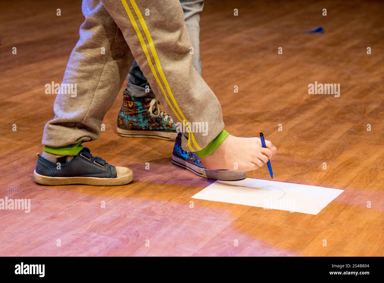 Child draws with his foot with felt tip pen on paper, kid in ...