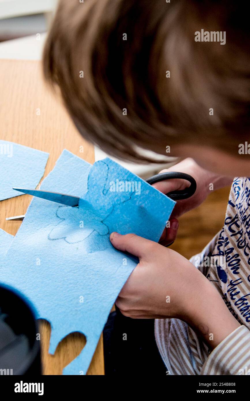 Child makes a craft from colored paper, kid draw in kindergarten ...