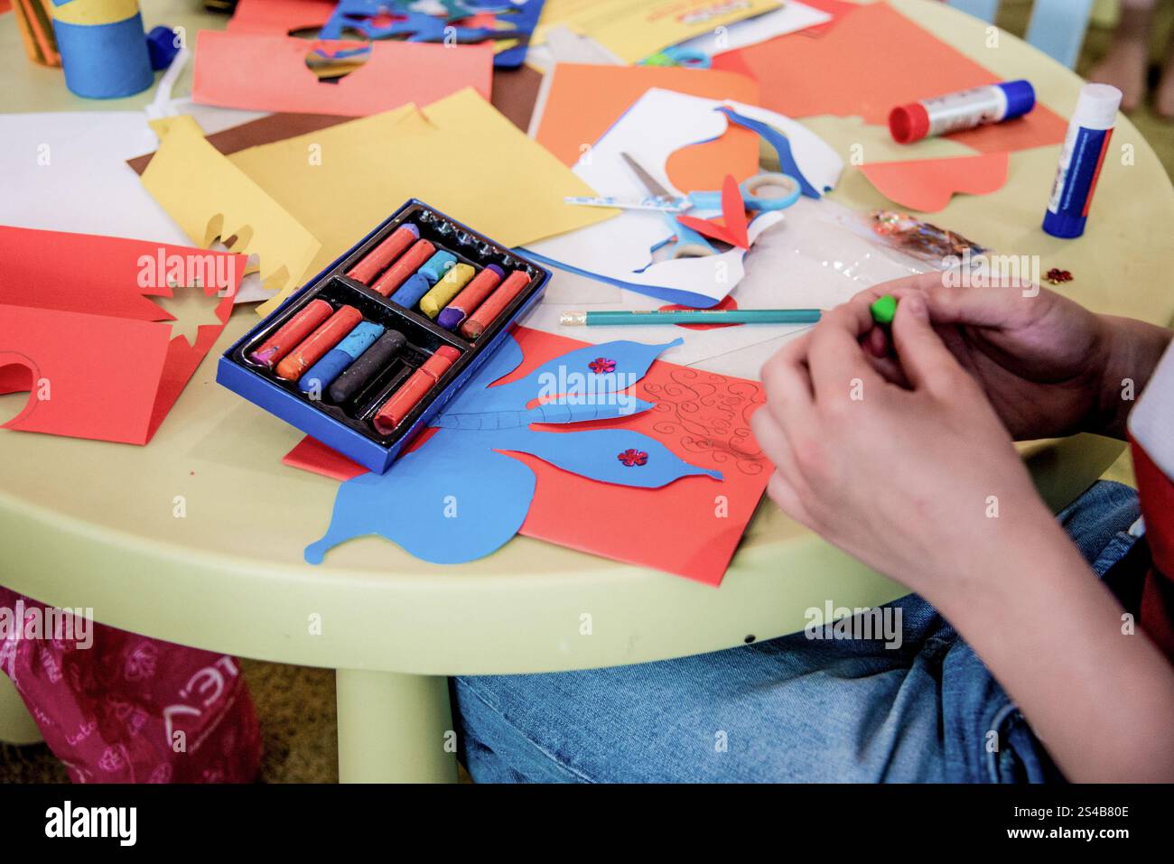 Child makes a craft from colored paper, kid draw in kindergarten ...