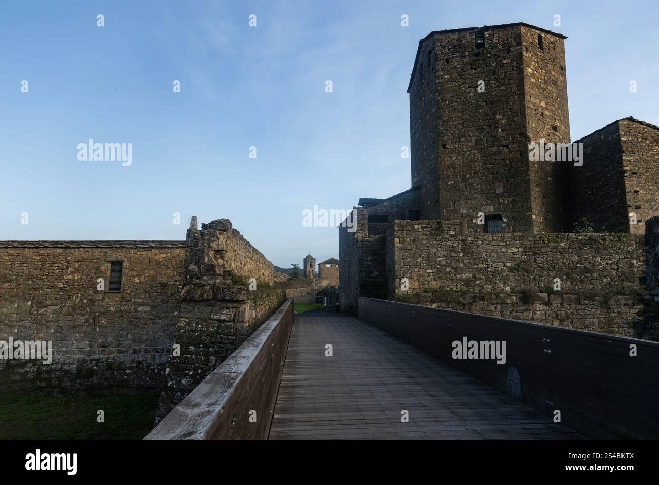 Stone fortifications and tower with a wooden walkway leading into the ...