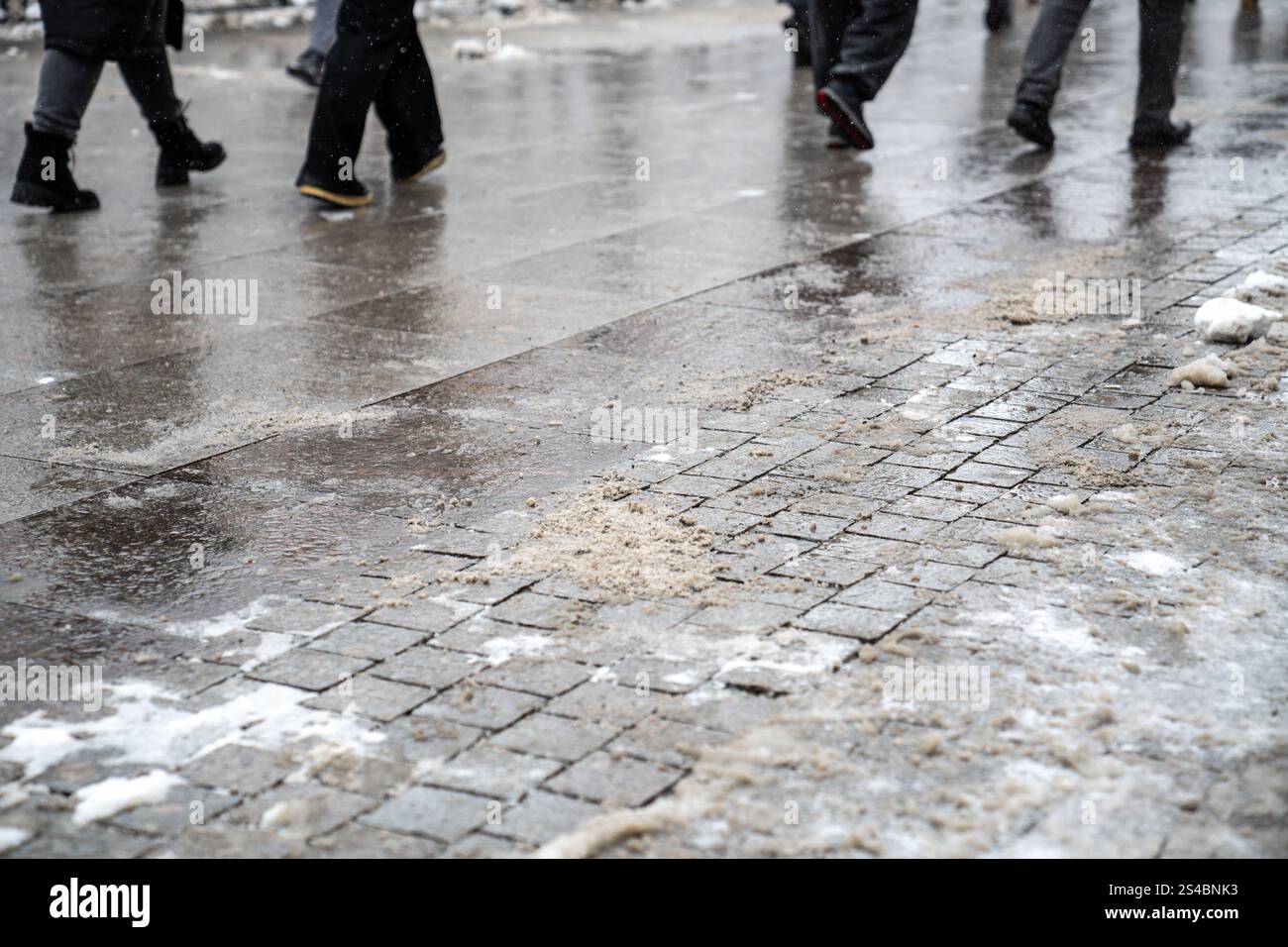 Anti-icing chemicals. People walking on the street treated with ...
