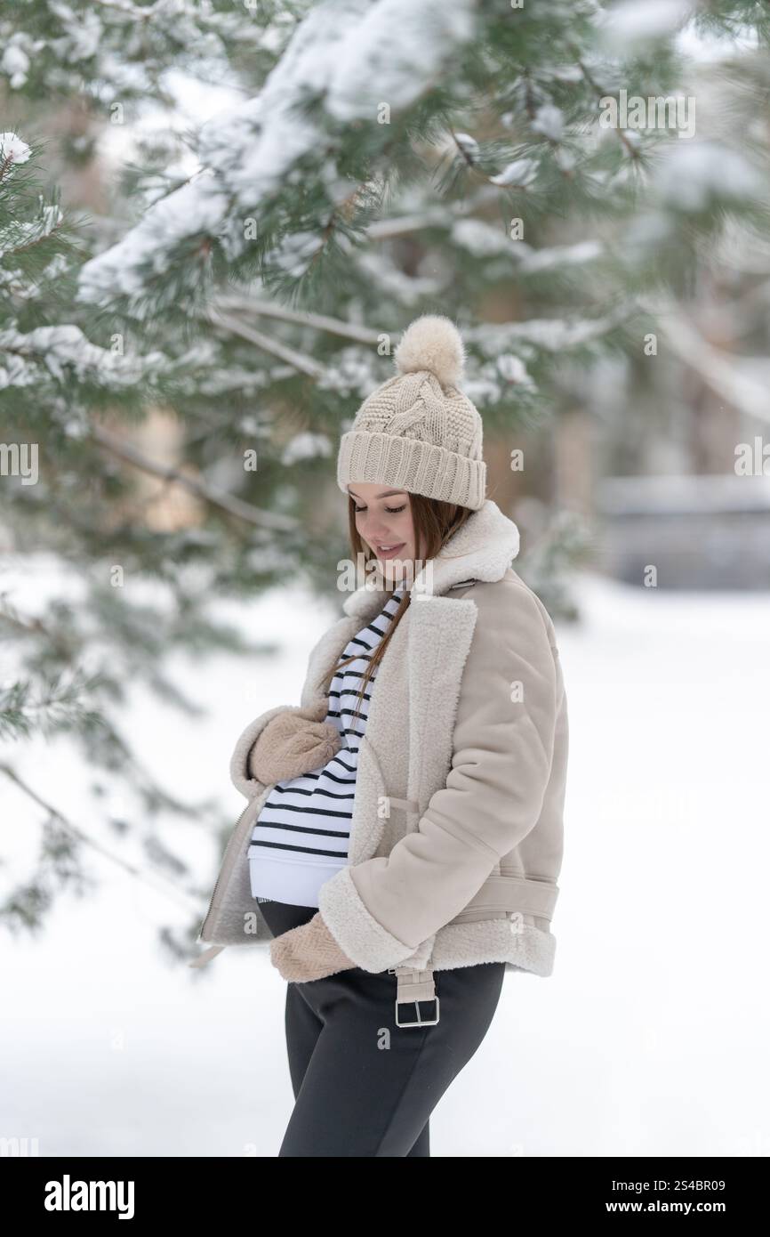 Gen z pregnant woman in a snowy winter forest with copy space ...