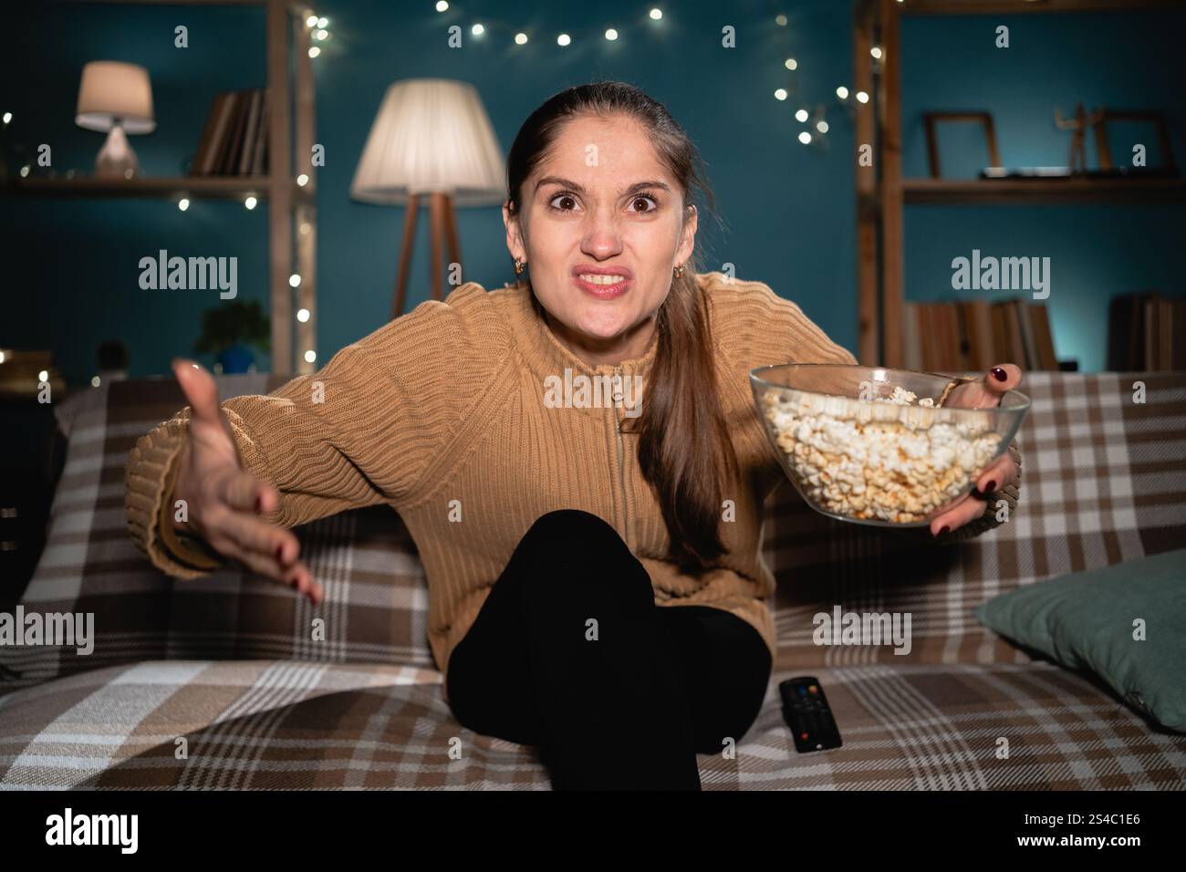 Emotional woman football fan eating popcorn and watching match during ...