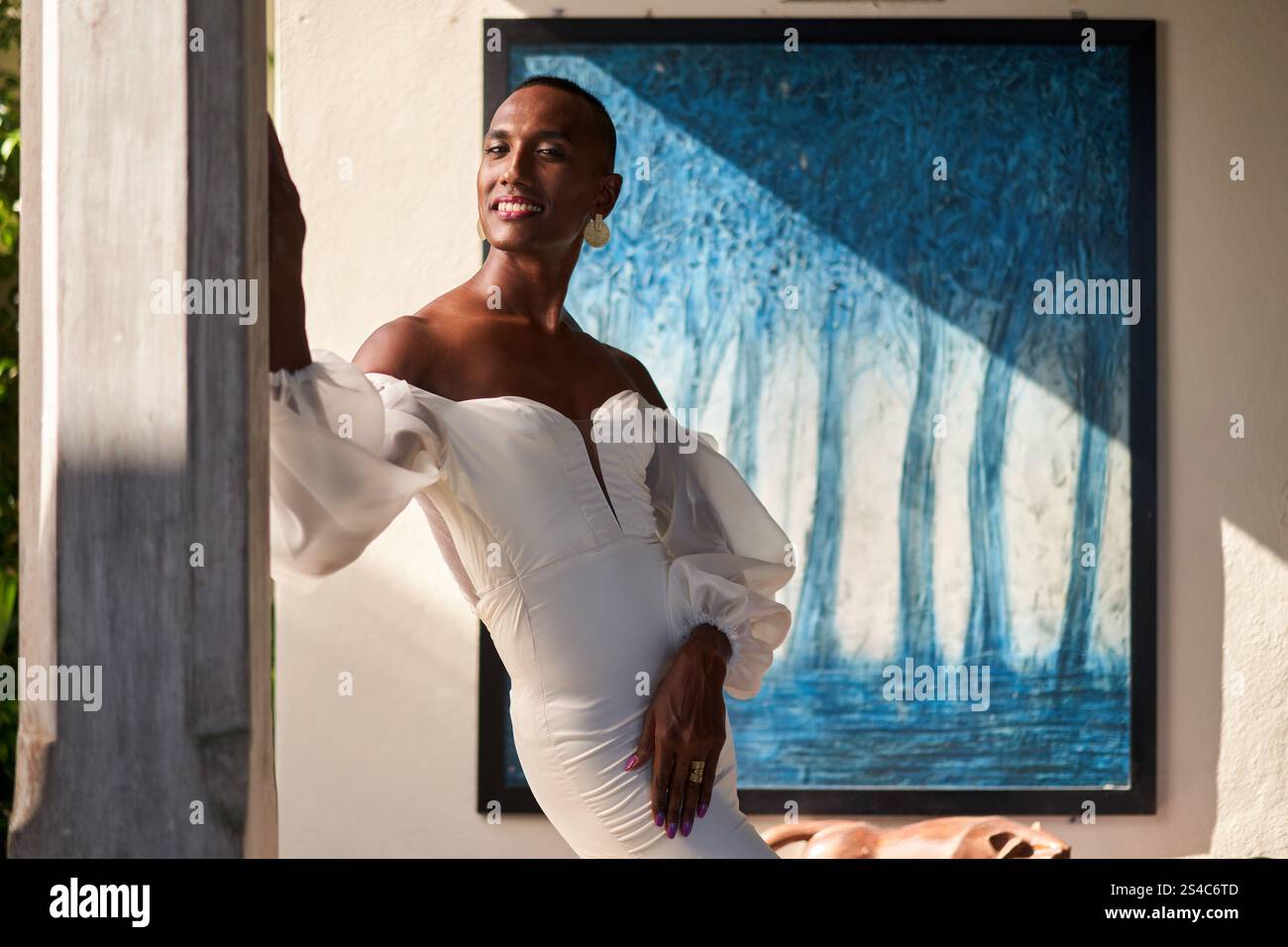 Gender-fluid person in white bridal dress stands elegantly in villa ...
