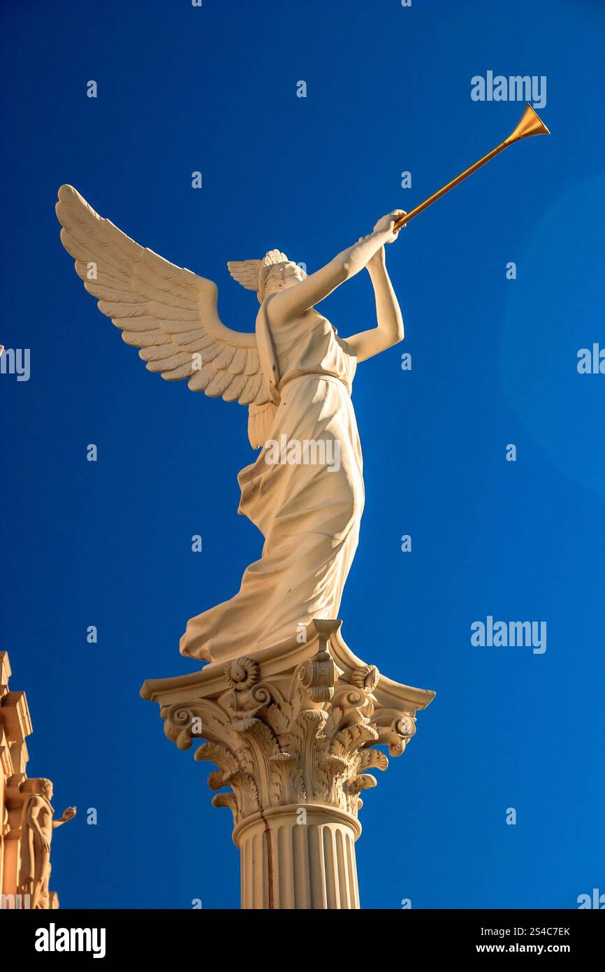 A statue of a woman holding a trumpet and wings. The statue is white ...