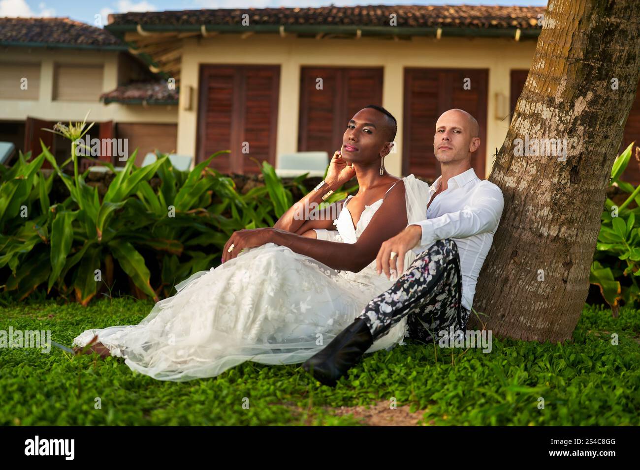Gender fluid person in white dress, LGBTQ groom in suit at tropical ...