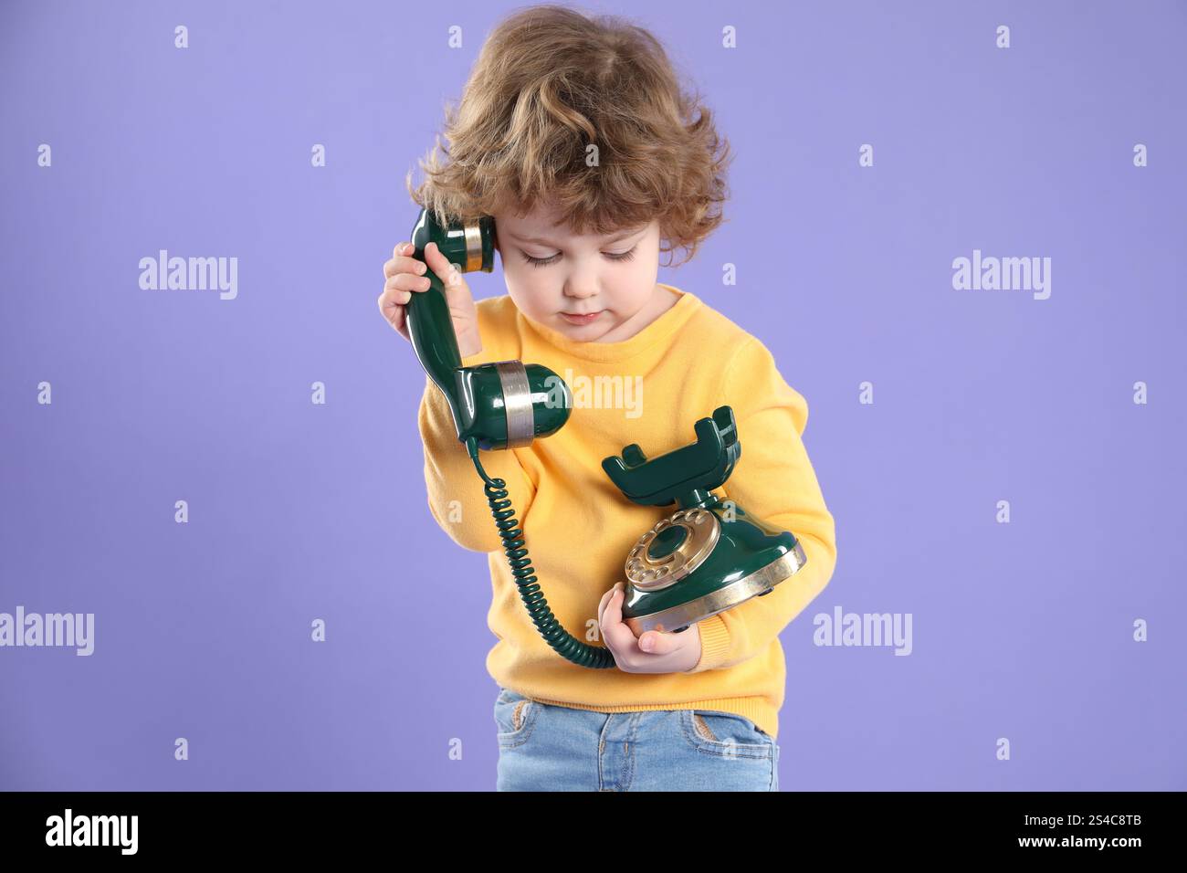 Cute little boy with old telephone on violet background Stock Photo - Alamy