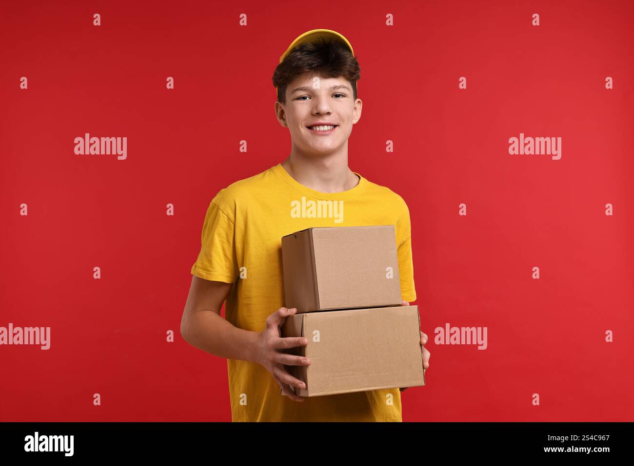 Teenage boy with parcels working as courier on red background Stock ...