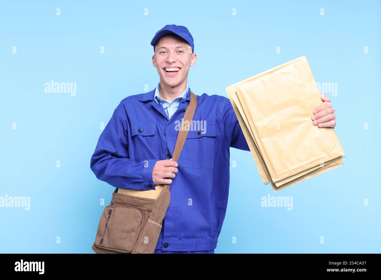Happy postman with bag giving envelopes on light blue background Stock ...