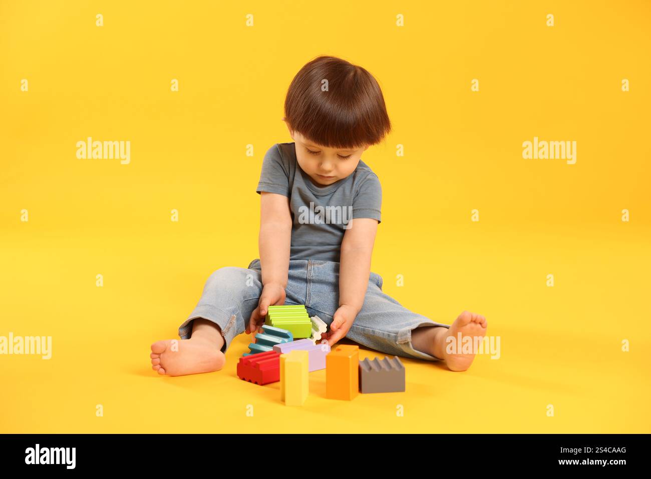 Cute little boy playing on yellow background Stock Photo - Alamy