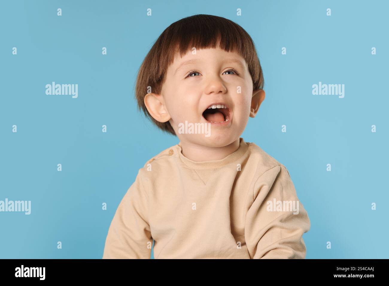 Portrait of emotional little boy on light blue background Stock Photo ...