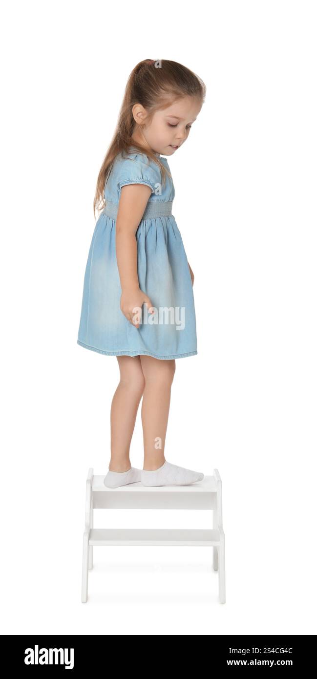 Little girl standing on step stool against white background Stock Photo ...