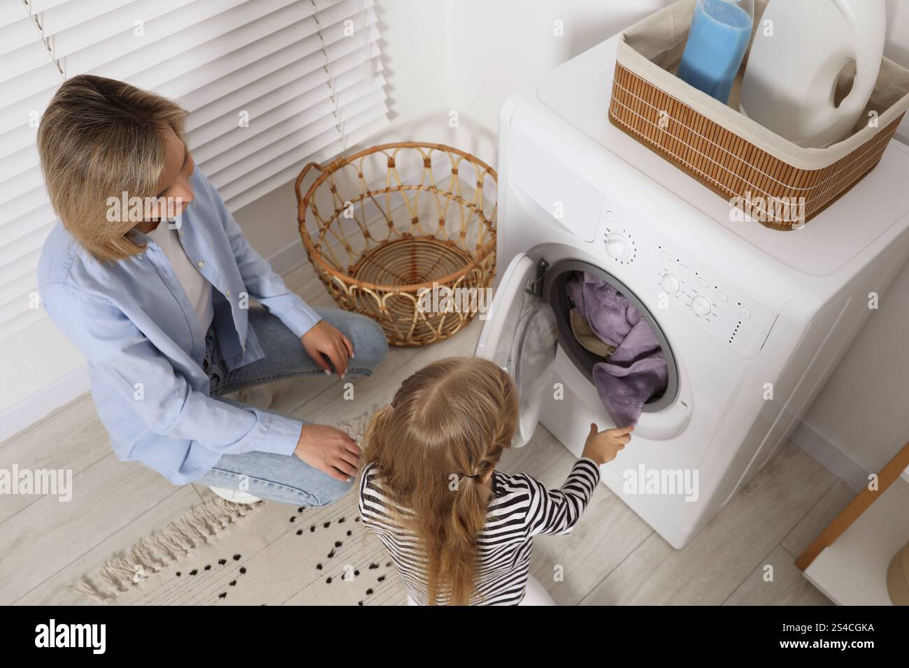 Little girl helping her mom doing laundry at home, above view Stock ...