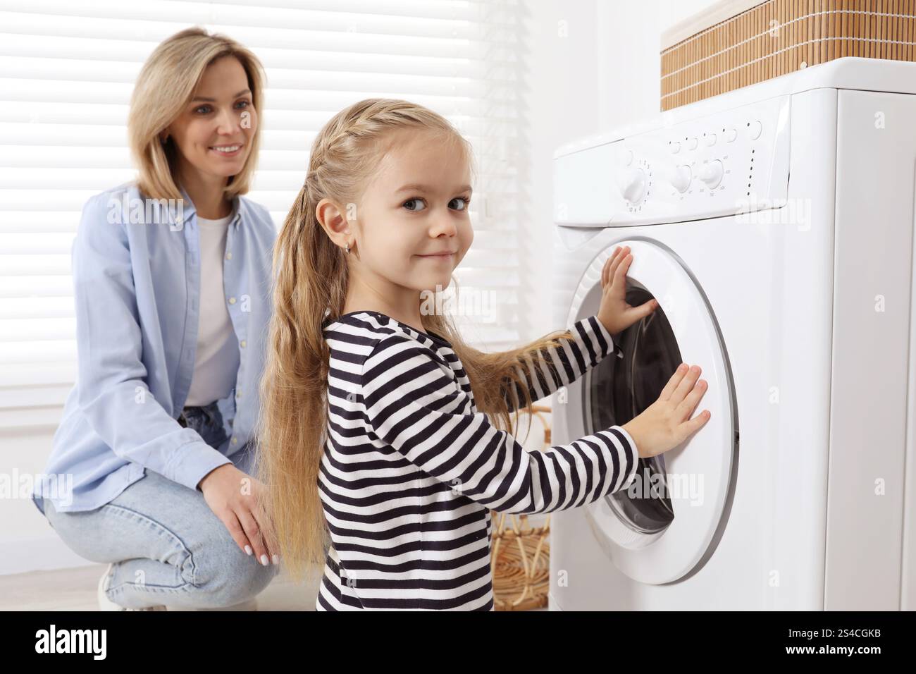 Little girl helping her mom doing laundry at home Stock Photo - Alamy