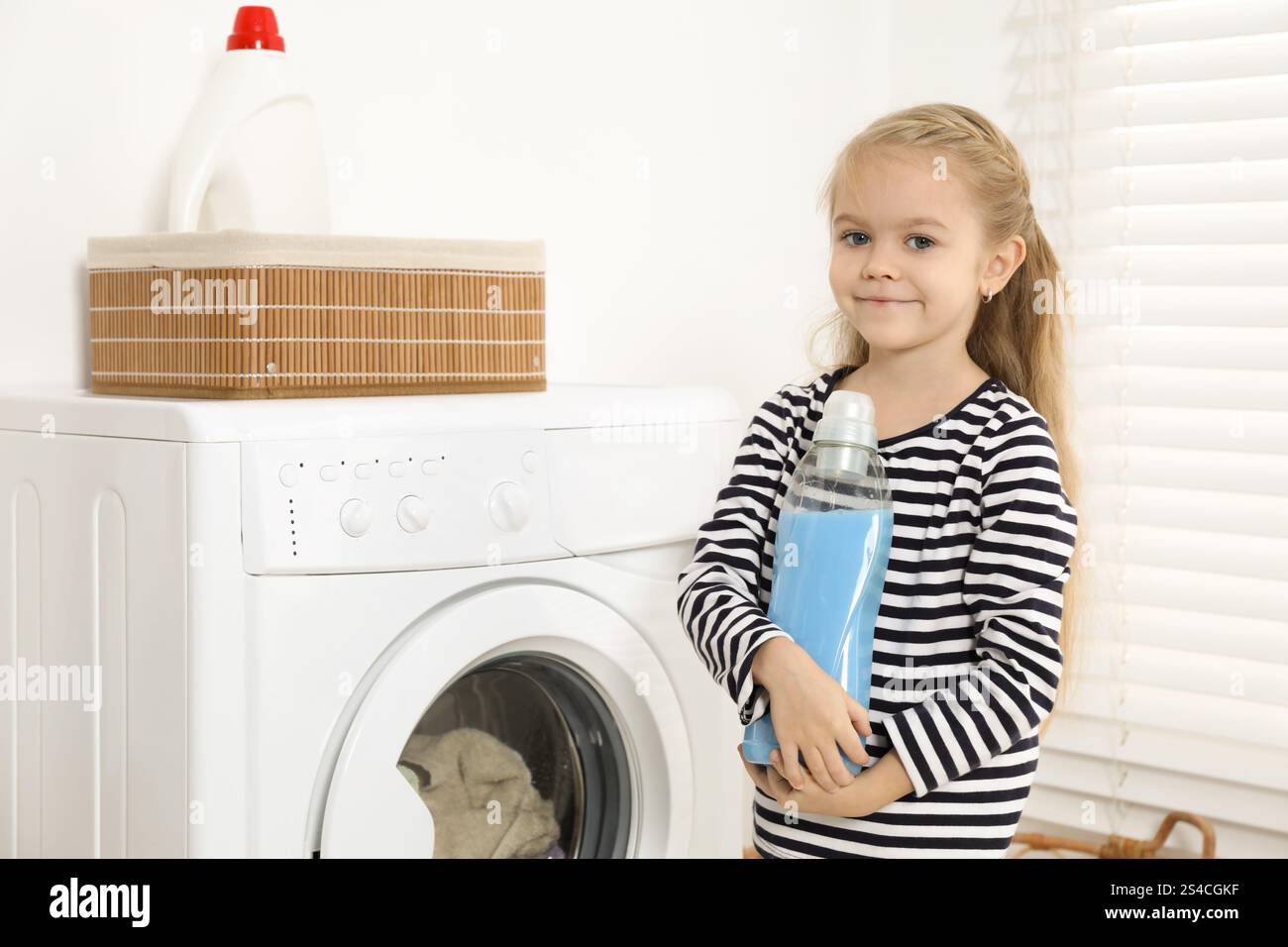 Little helper. Cute girl doing laundry at home Stock Photo - Alamy