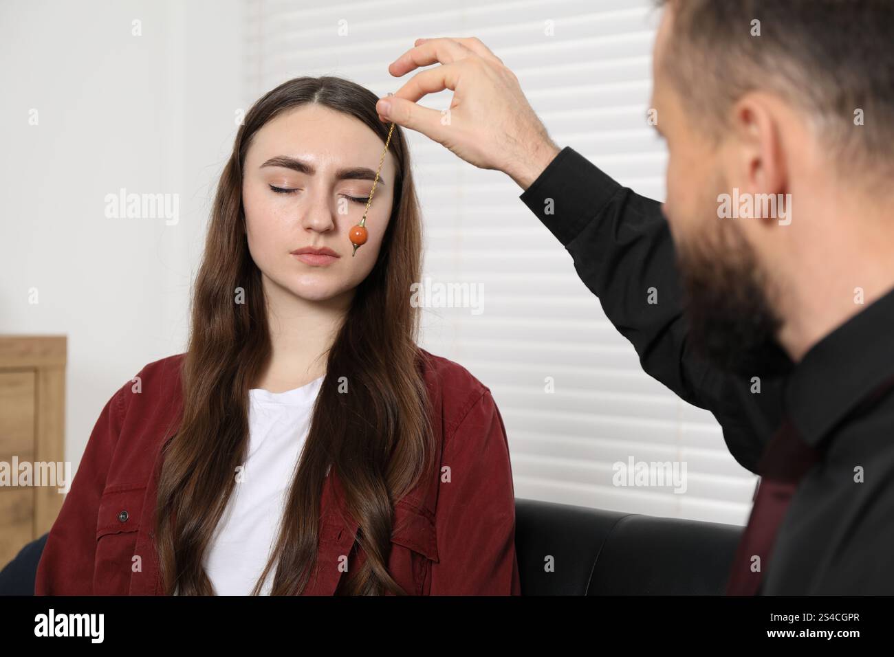 Psychologist using pendulum while working with patient during hypnosis ...