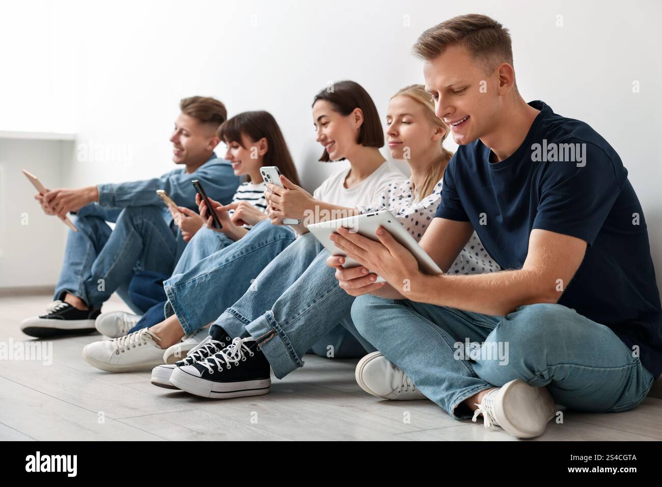 Group of people using different gadgets on floor indoors. Modern ...