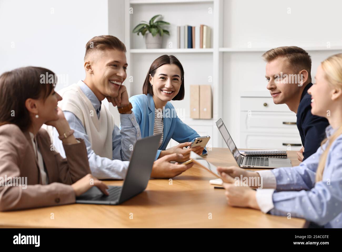 Group of people using different gadgets at wooden table in office ...